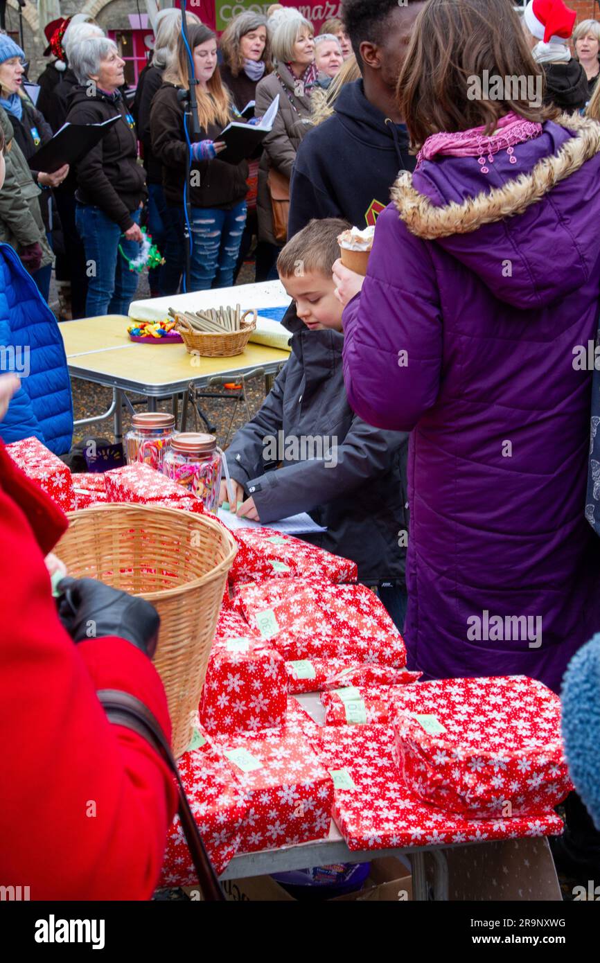 Festively wrapped mystery raffle prizes displayed at a Christmas carol ...