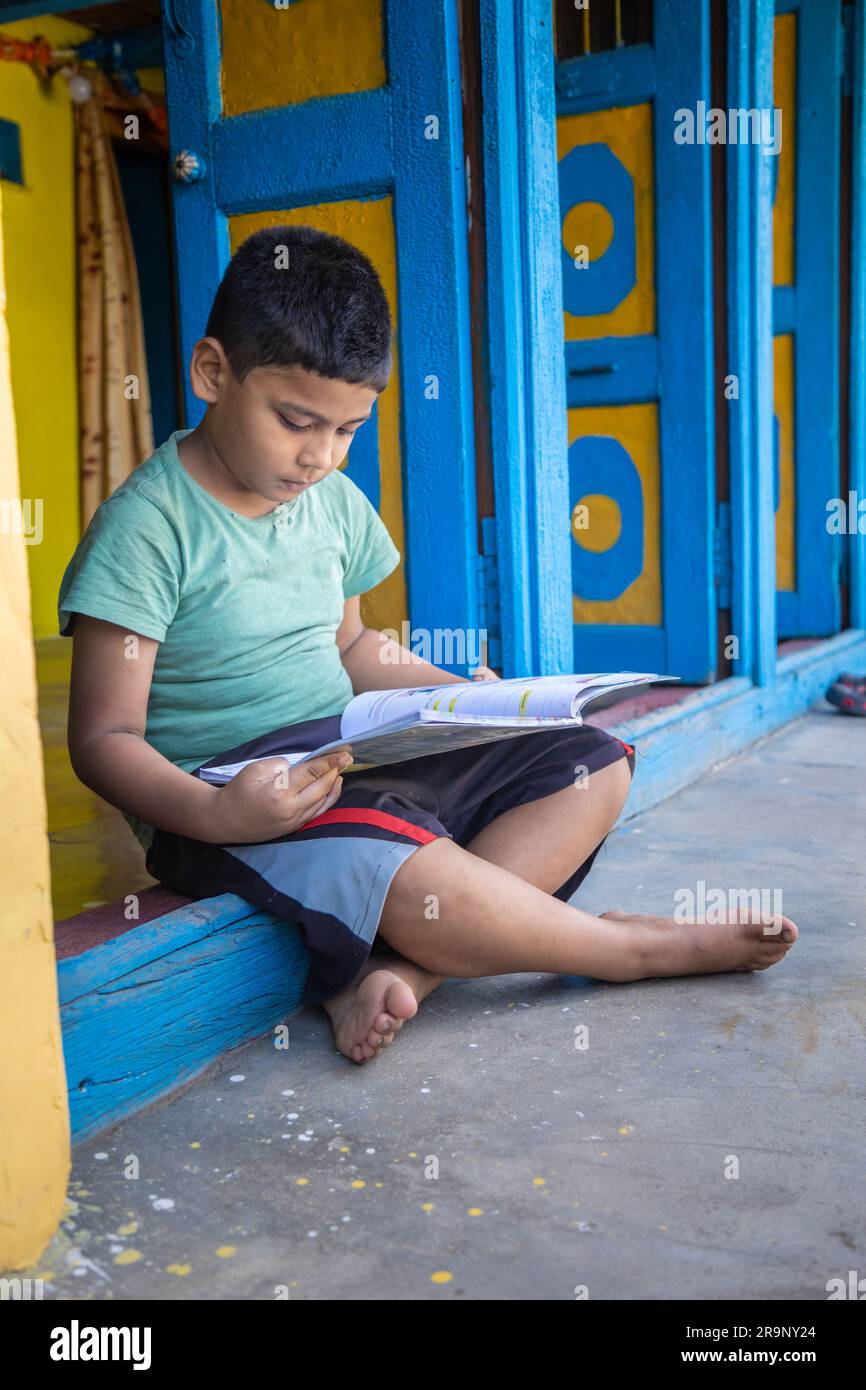 Elementary age child reading his school book. He is sitting at his ...