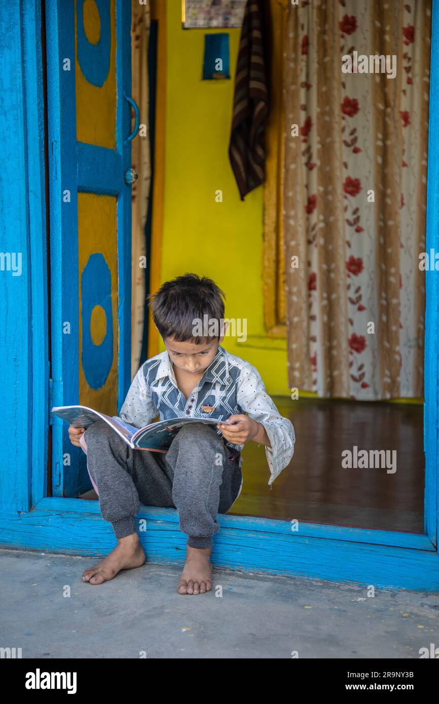 Elementary age child reading his school book. He is sitting at his ...