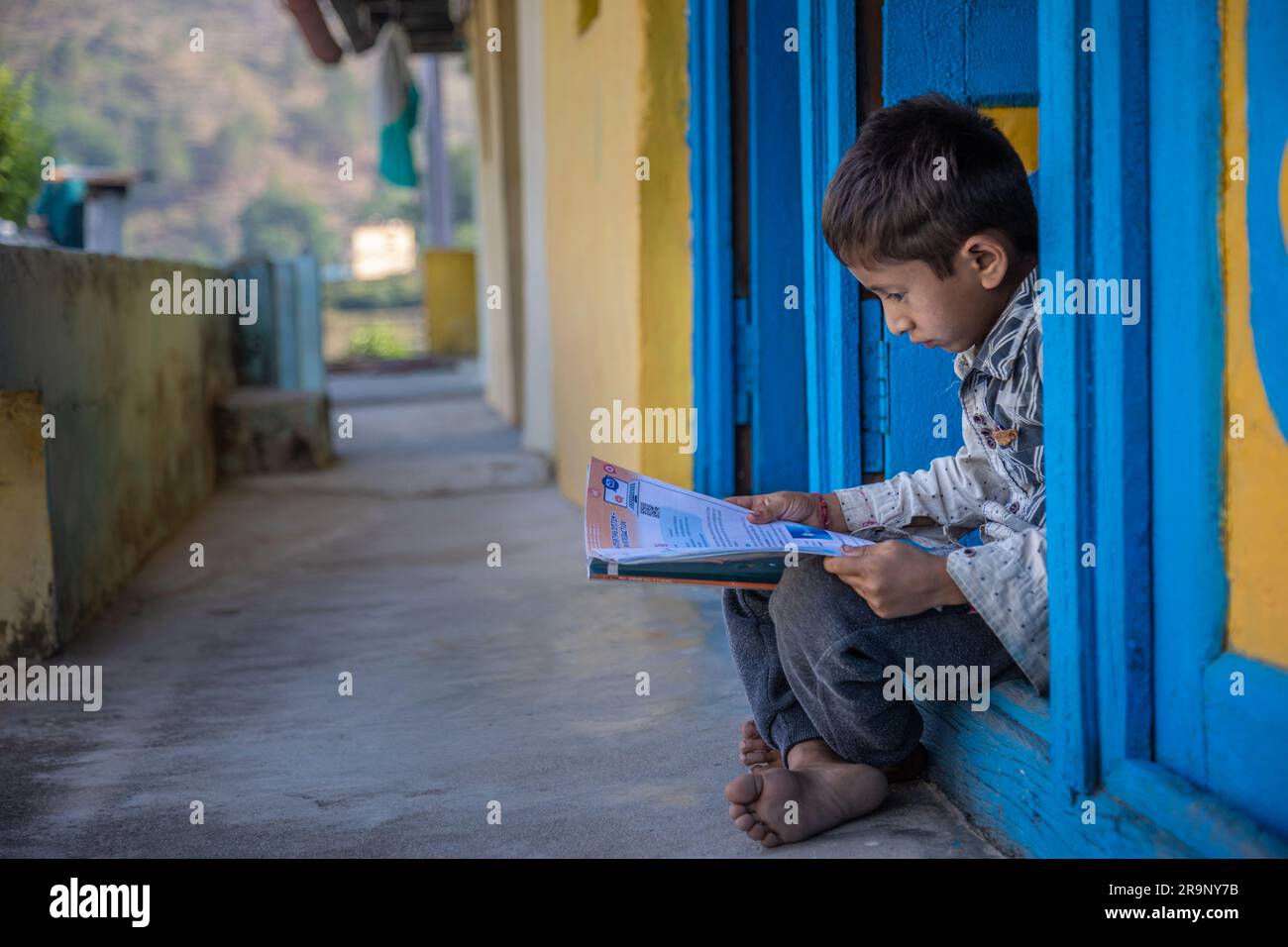 Elementary age child reading his school book. He is sitting at his ...