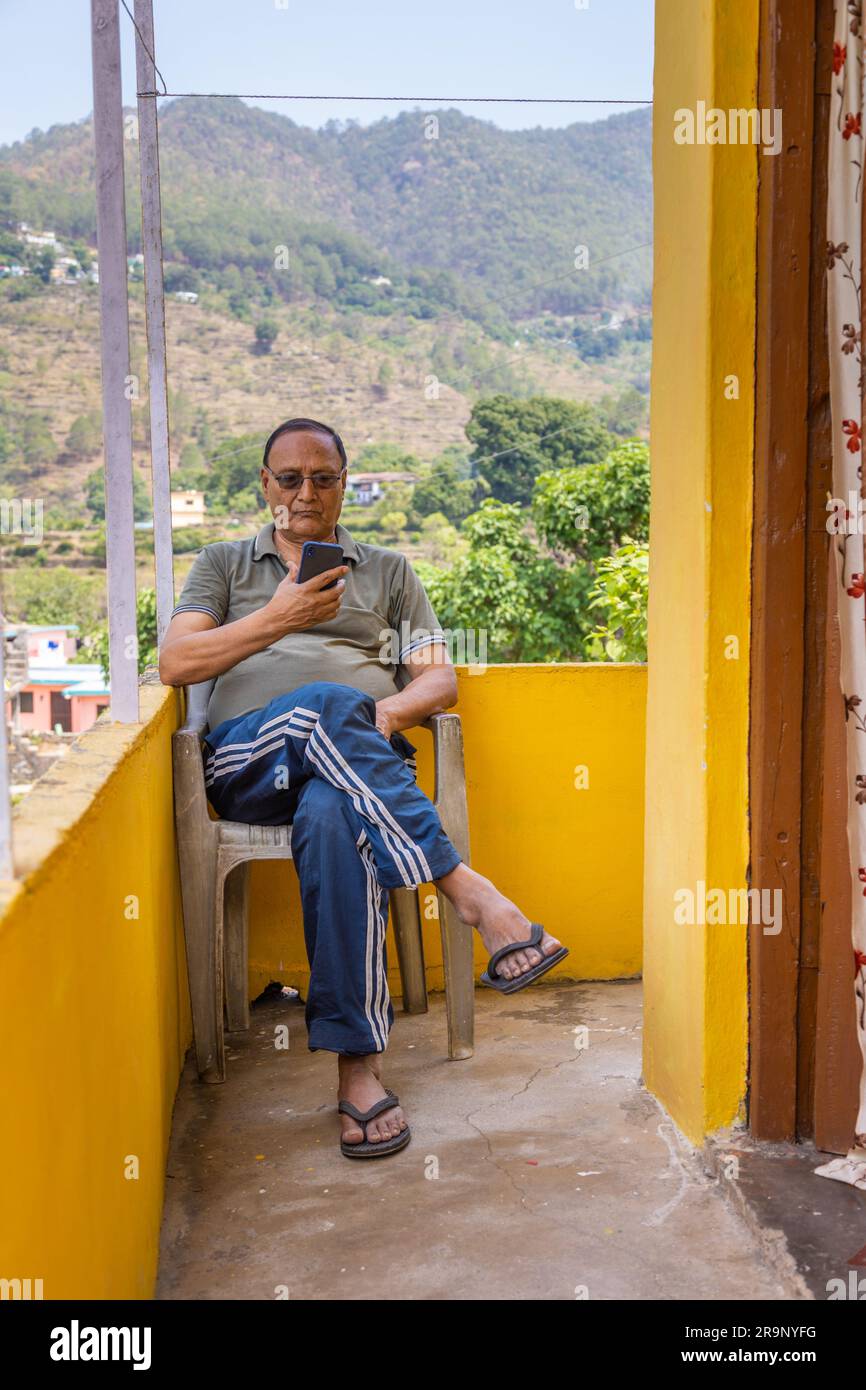 Modern Rural Farmer sitting at balcony of his village house, holding ...