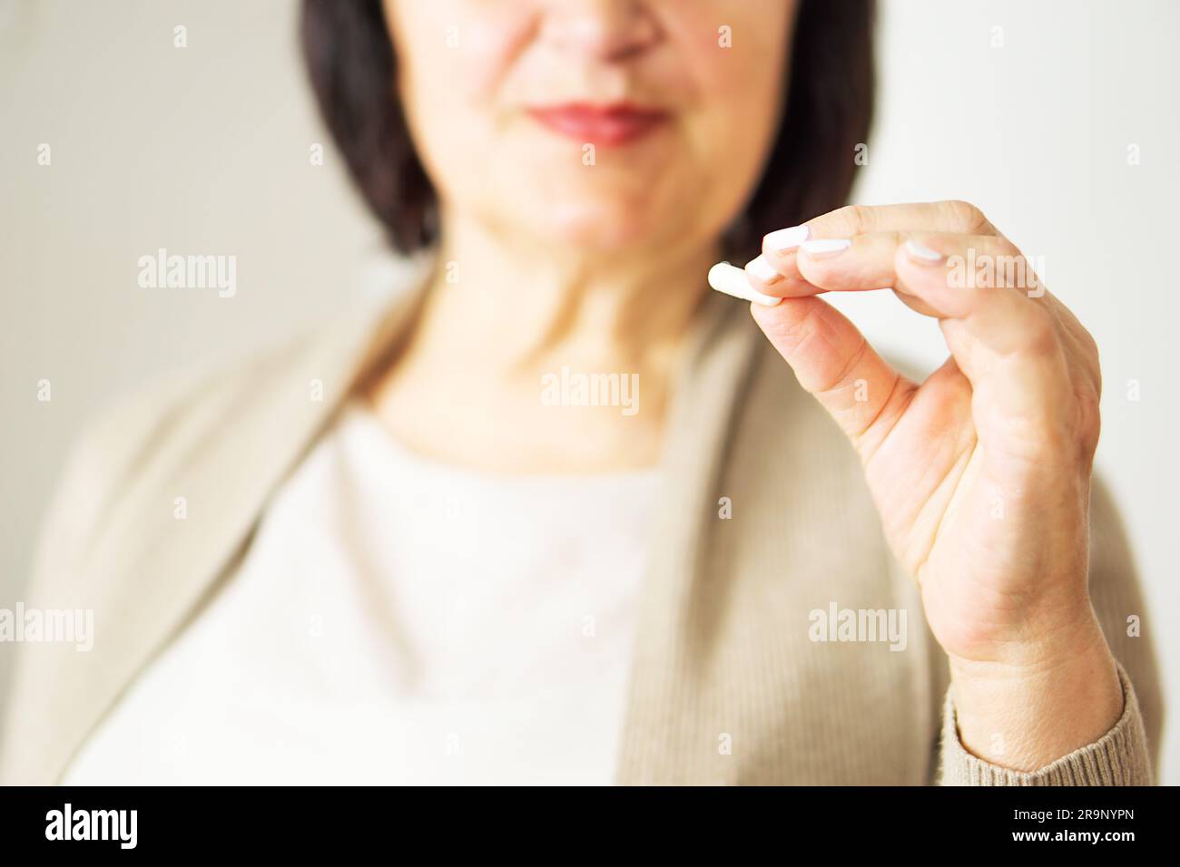 A portrait of a retired woman in casual clothes at home holding her ...