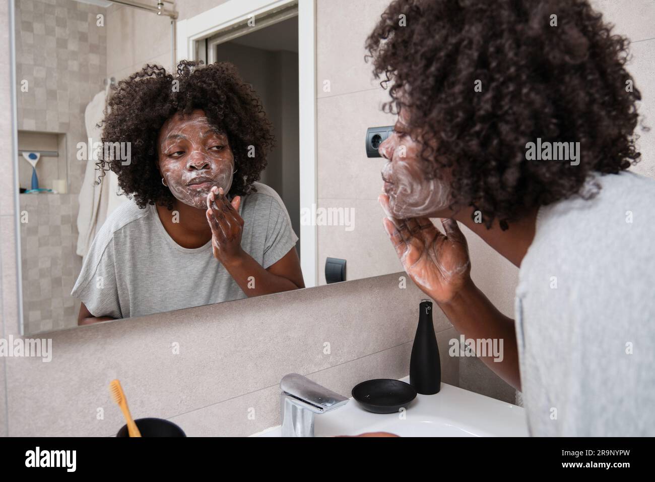 African woman washing her face skin with soap in bathroom Stock Photo ...