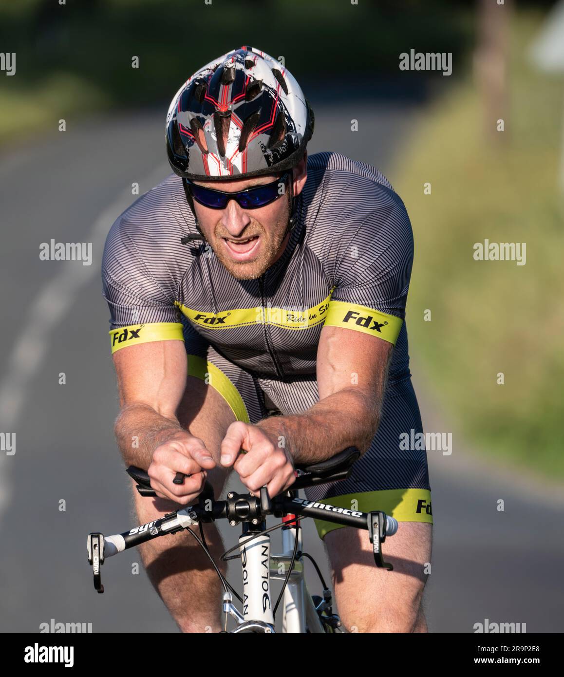 Male time trialist competing in an evening race on a sporting course at ...