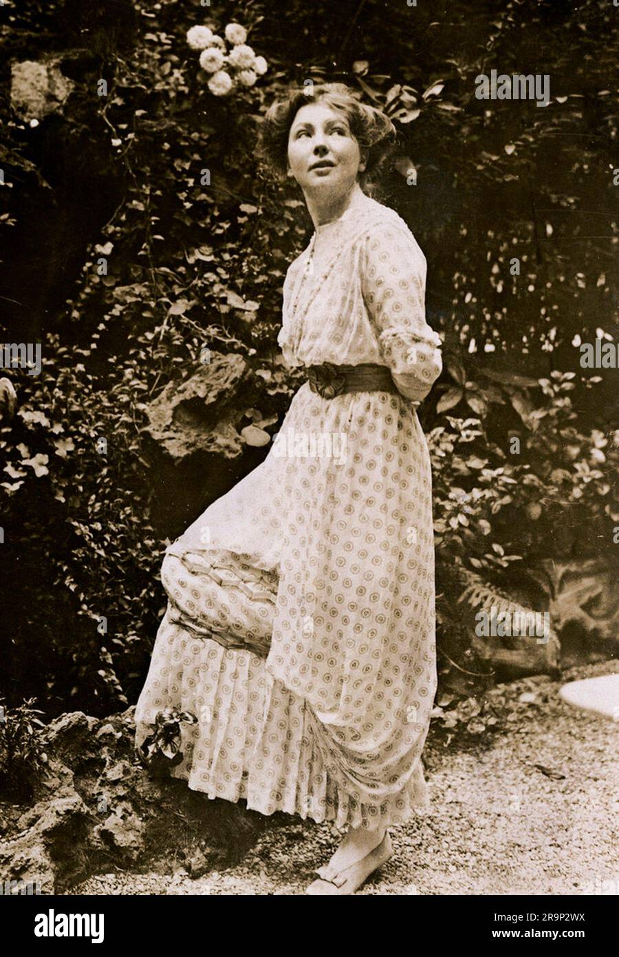 A portrait of Christabel Pankhurst standing in a garden. The photo is ...