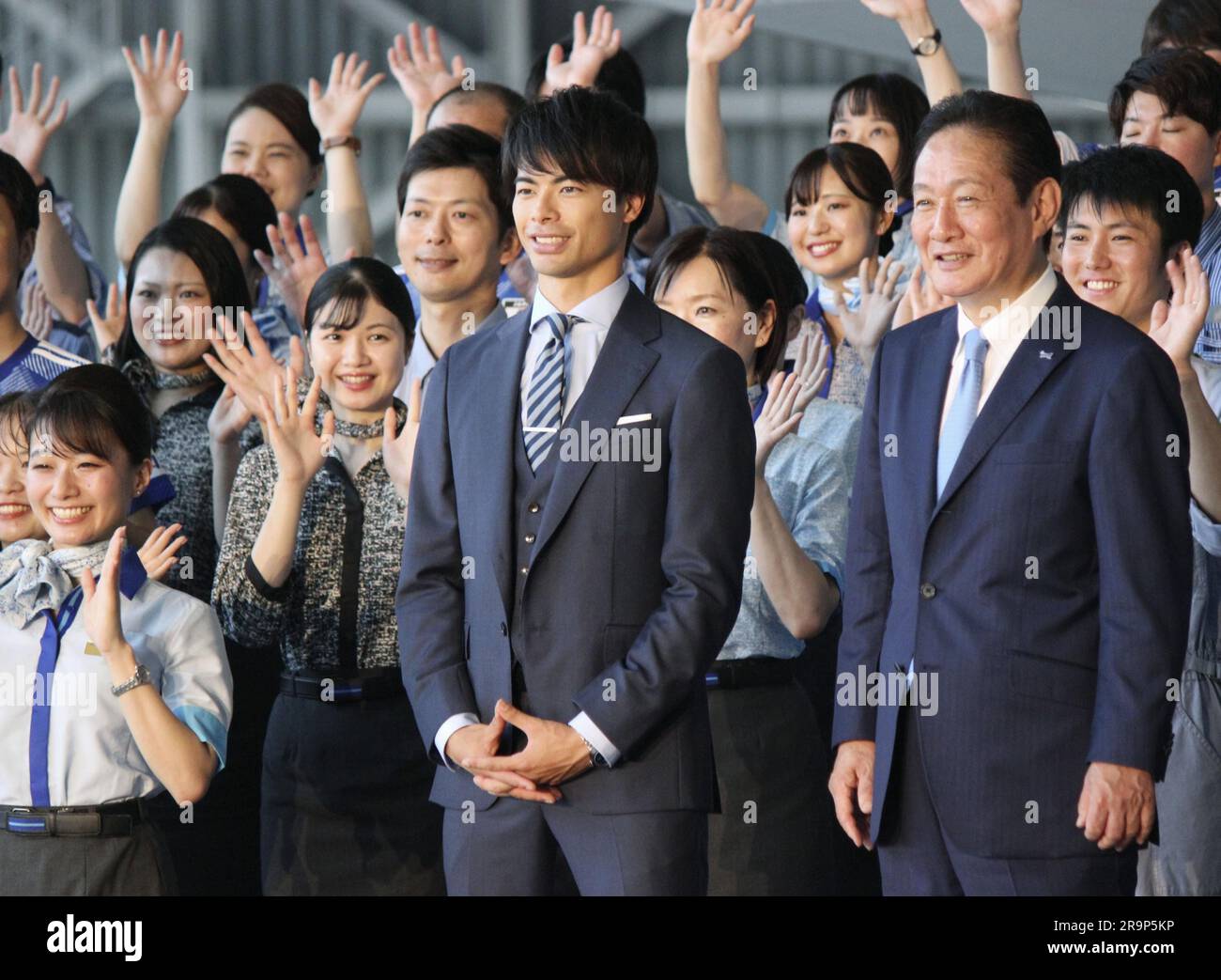 Japan international footballer Kaoru Mitoma (C) poses for a photo after signing a sponsorship ...