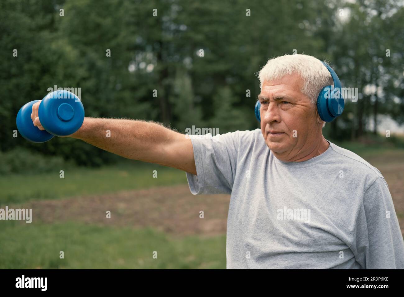 Senior man working out outdoors. Person lifting dumbbells. Old male ...