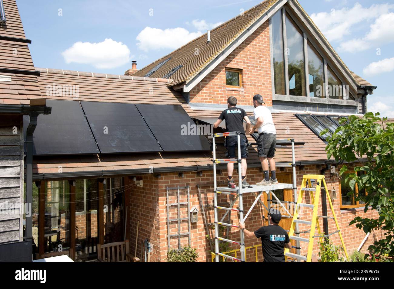 Two technicians installing black 410kW Perlite panels on tiled roof at ...