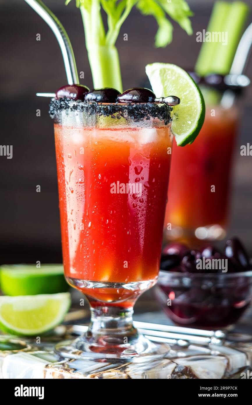 Refreshing Caesar cocktails with black salt rims, garnished with black ...