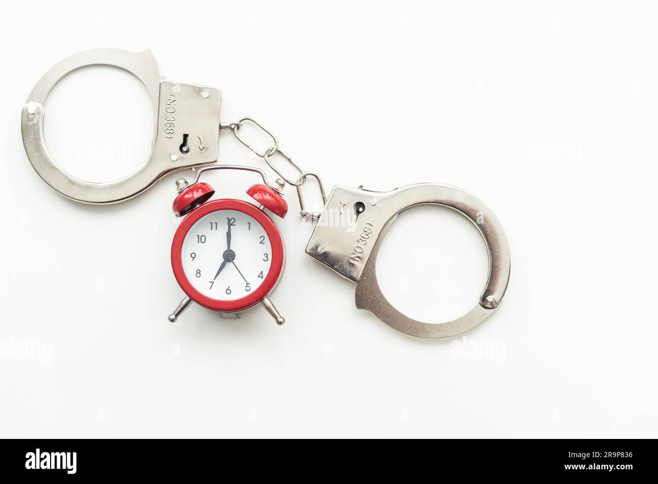 Gray metal handcuffs with clock on isolated muted pastel blue ...