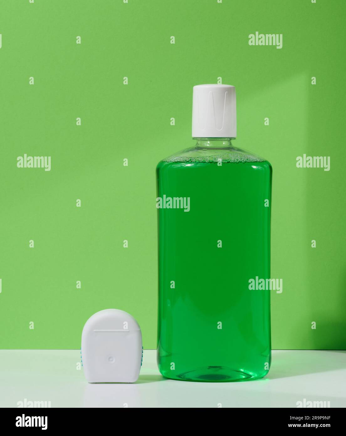 Refreshing mouthwash in a transparent plastic bottle and dental floss ...