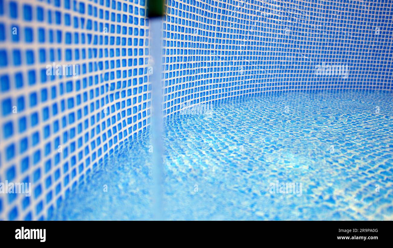 Water flowing from the hose into the pool filling. The inside of the ...