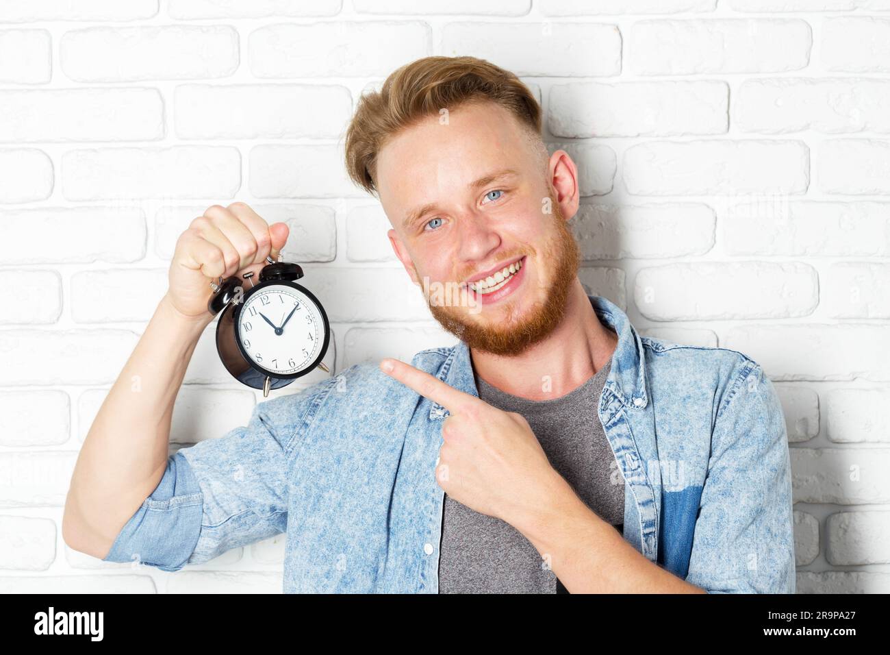 Young man looking alarm clock hi-res stock photography and images - Alamy