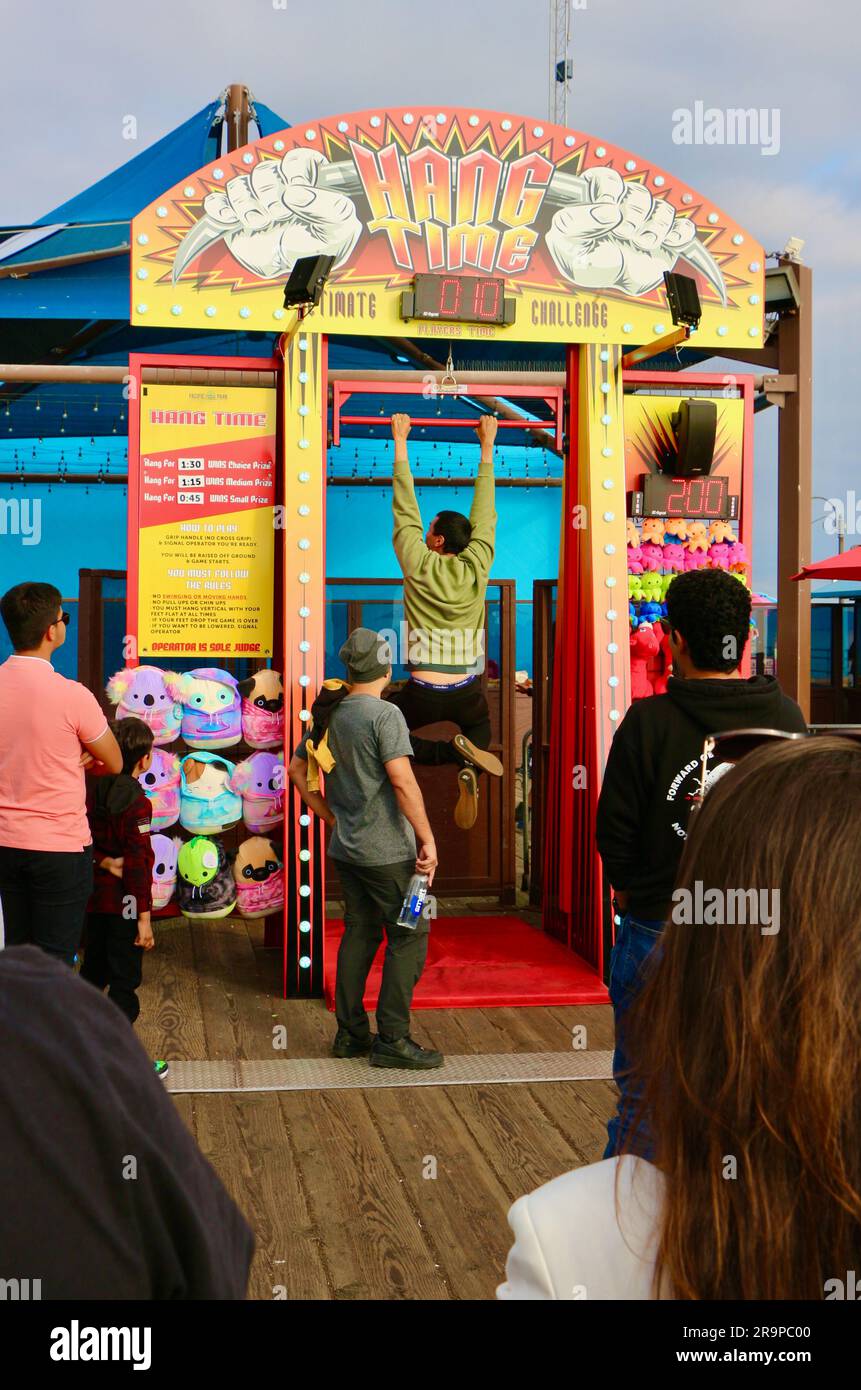 People watching a man hanging on a bar timed for a strength test ...