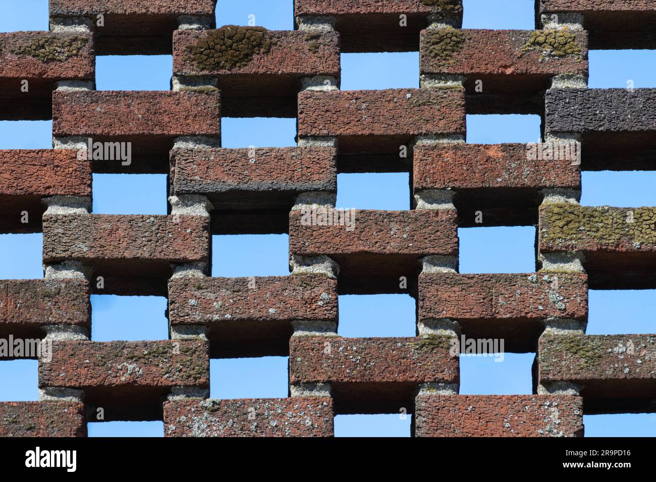 wall of open lattice bricklaying pattern with the blue sky peering ...