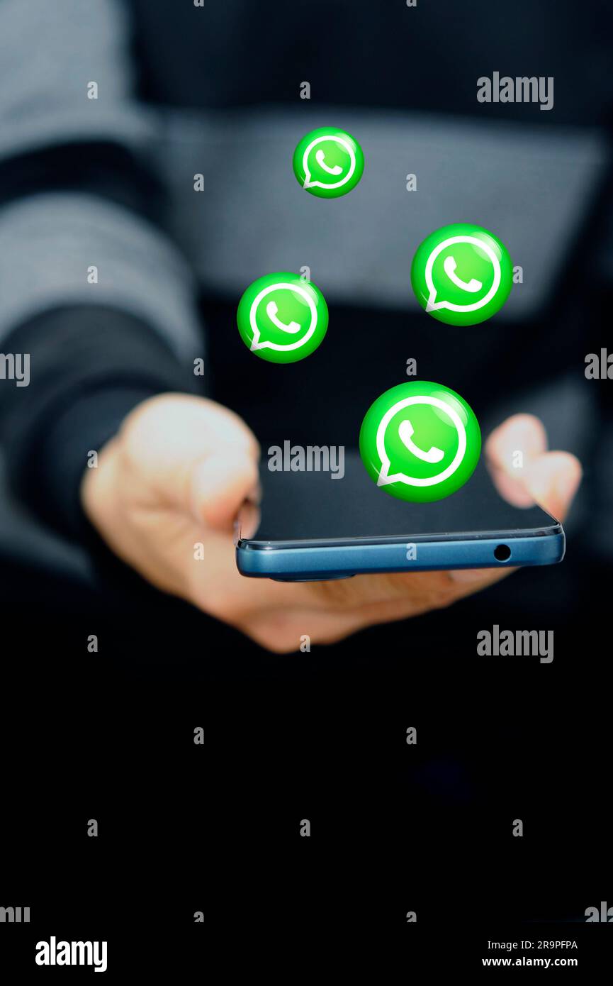 holding a mobile phone and whats app symbols over it Stock Photo - Alamy