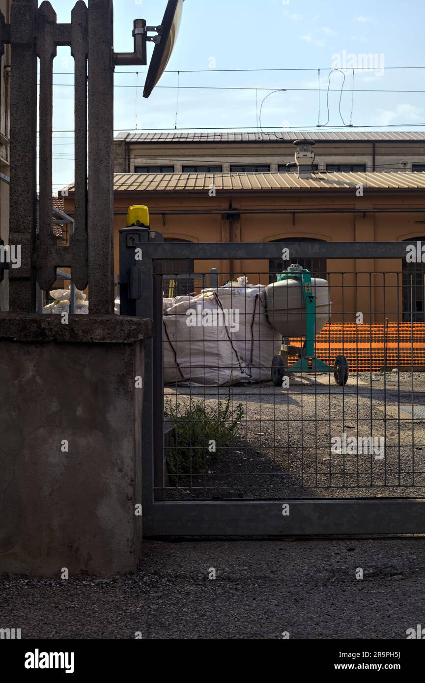 Railroad track and over head cables seen from a pavement behind a fence ...