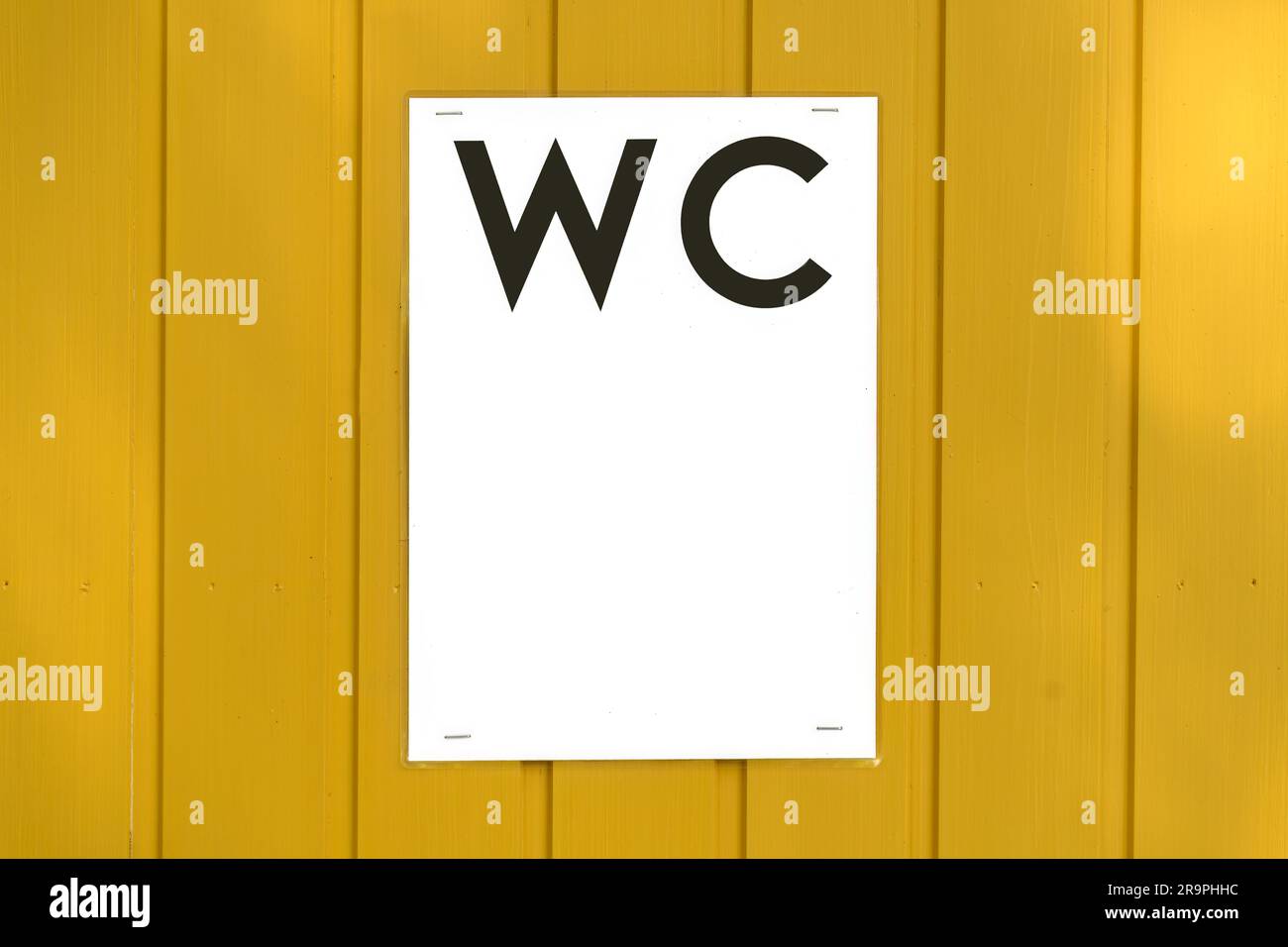 Laminated WC sign stapled to the yellow wooden door, close up with copy ...