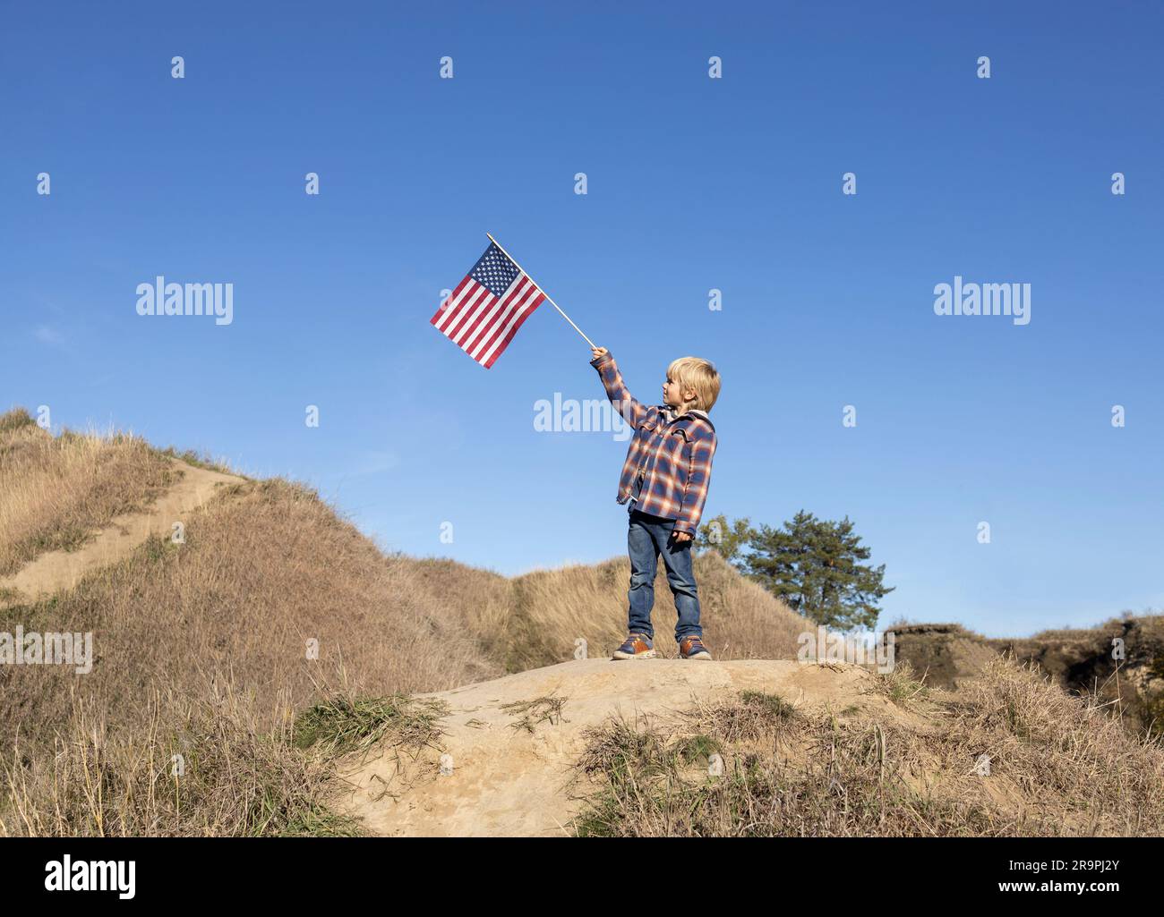 Patriotic boy 6 years old proudly raised the American flag against the ...