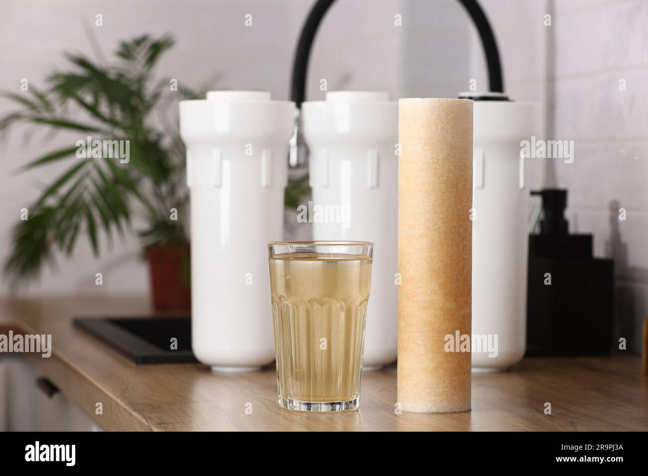 Water filter cartridge used and a glass of rusty water brown coloring ...