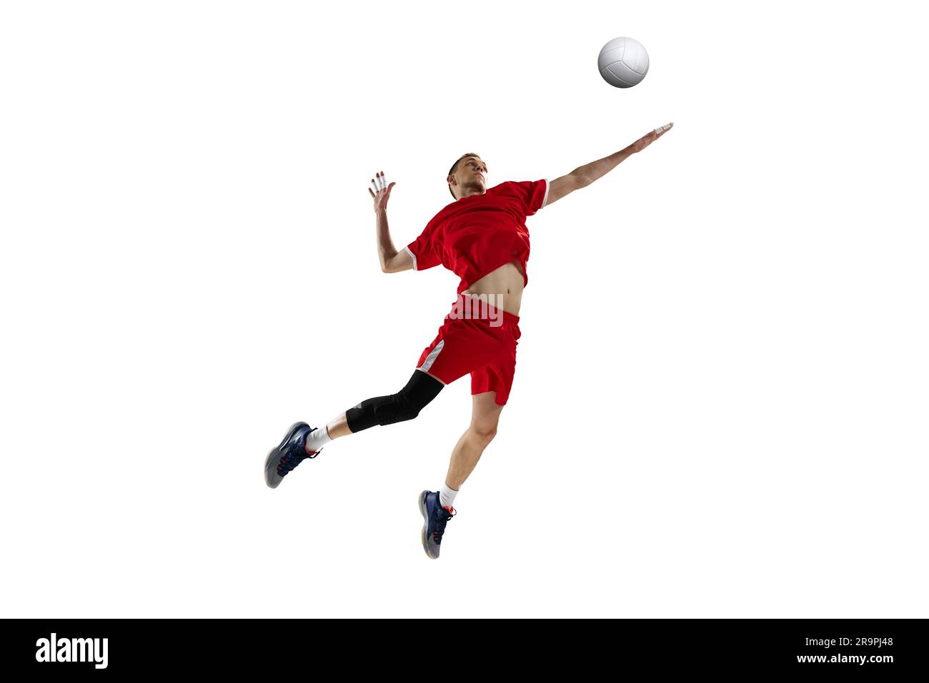 Young man, professional athlete in red uniform in motion, hitting ball ...