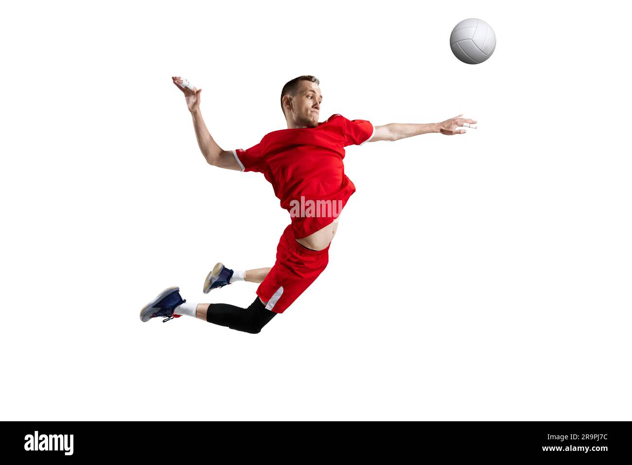 Young man, professional athlete in red uniform in motion, hitting ball ...