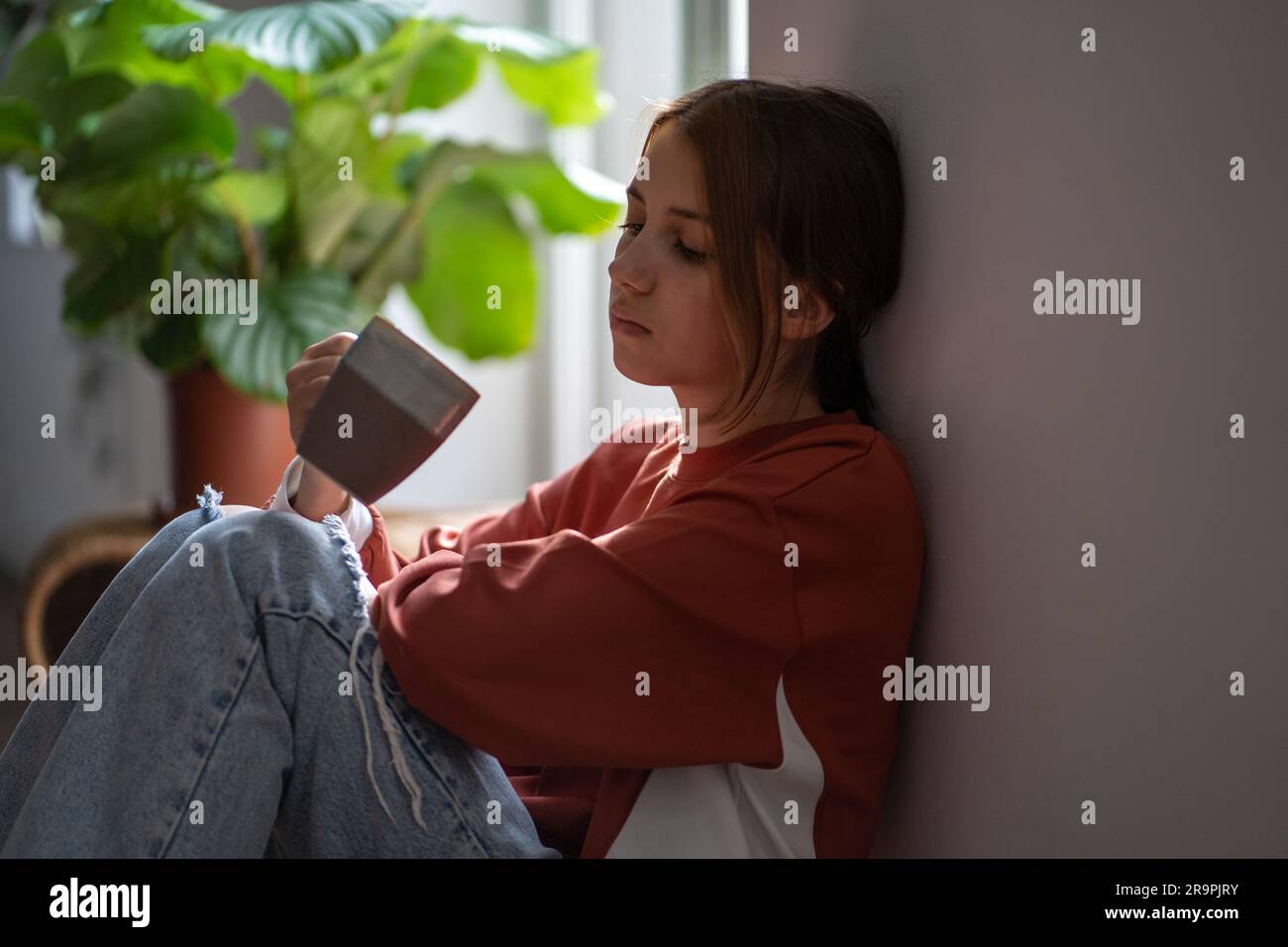 Frustrated teen girl sits on floor with cup sad devastated thinking ...