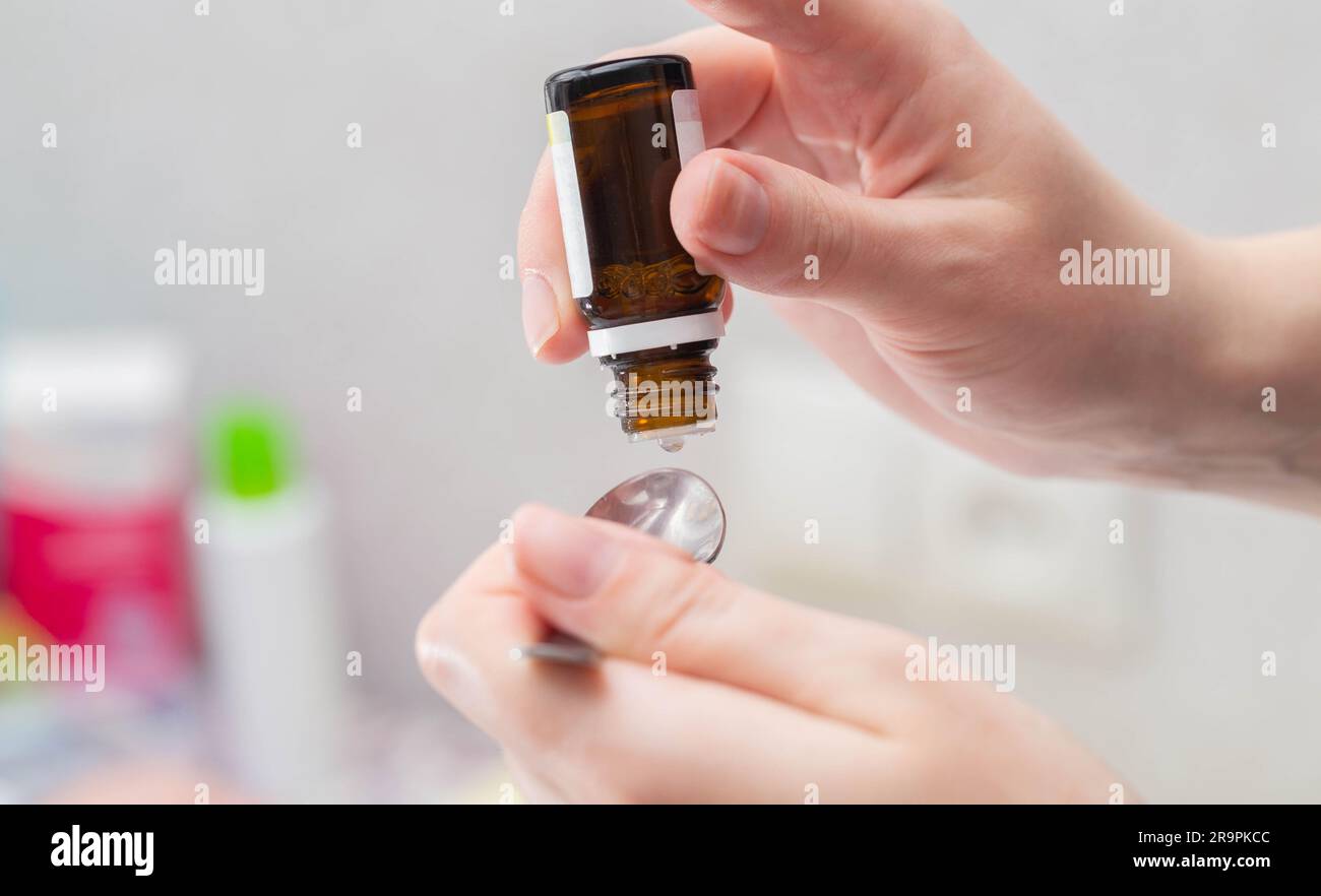 Mother drips medicinal drops into a spoon for the treatment of an ...