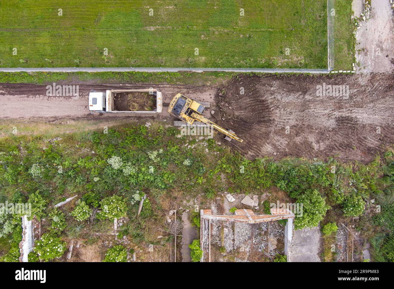 Aerial view of an excavator working removing earth and loading it into a truck dumper on a ...