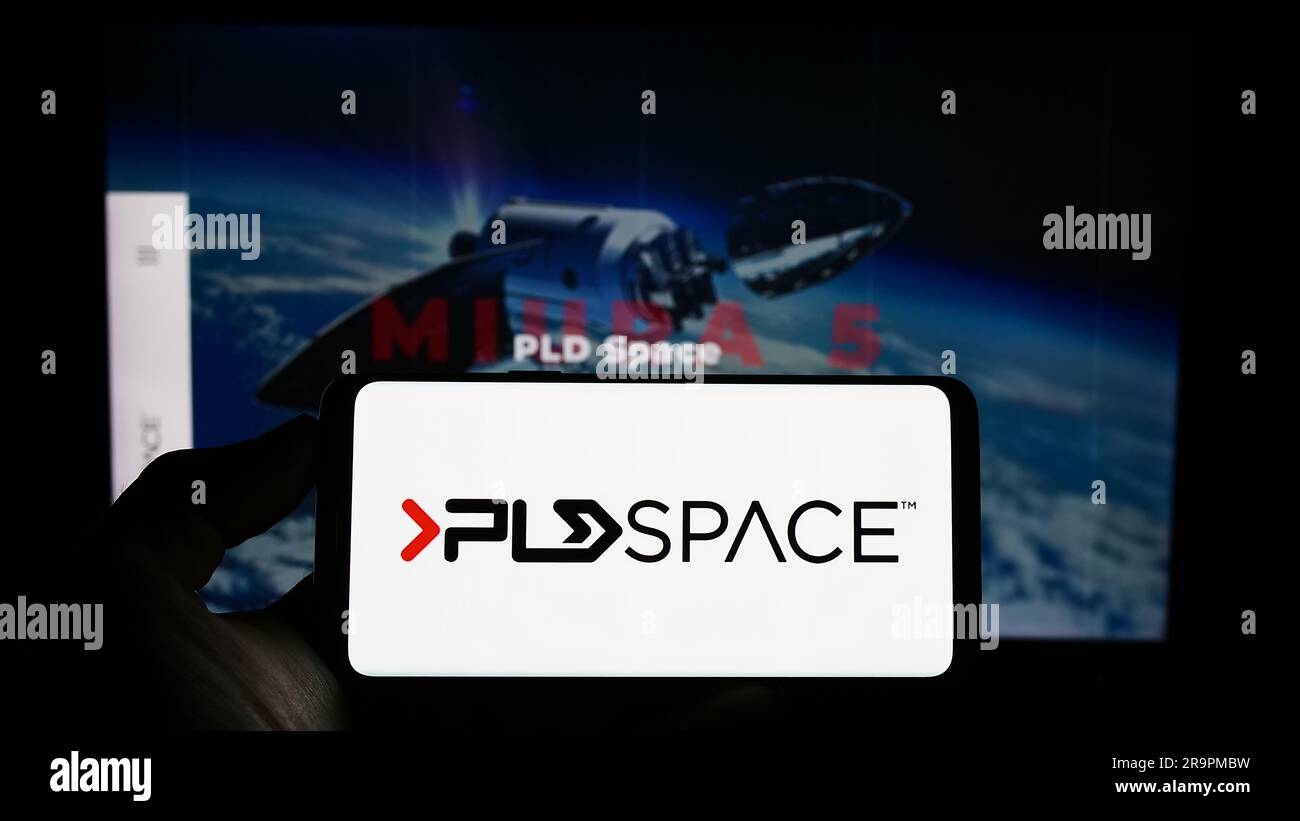 Person holding mobile phone with logo of company Payload Aerospace S.L ...