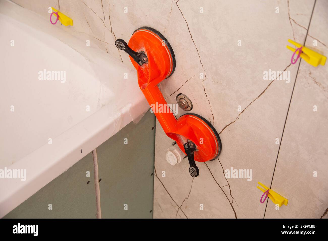 An orange suction cup on a porcelain tile wall. Tile leveling system ...