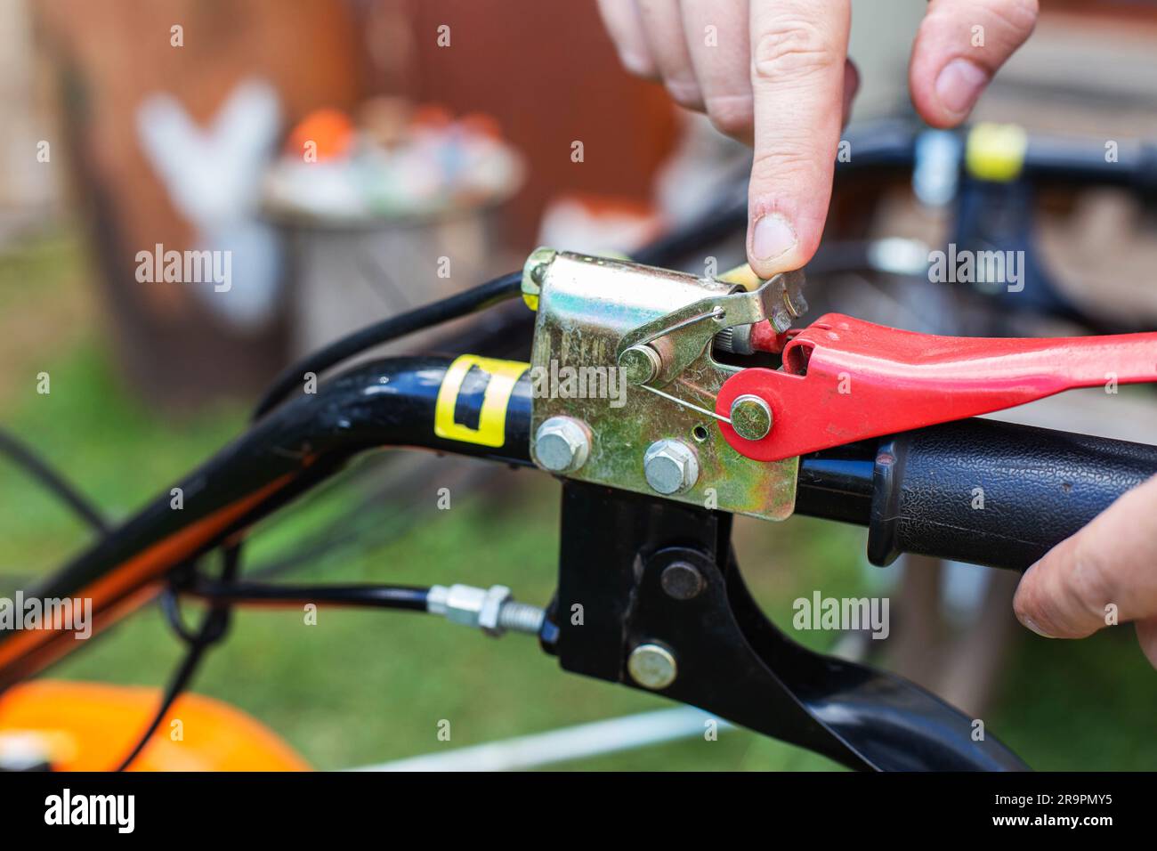 A man presses the handle of the safe shutdown of a walk-behind tractor ...