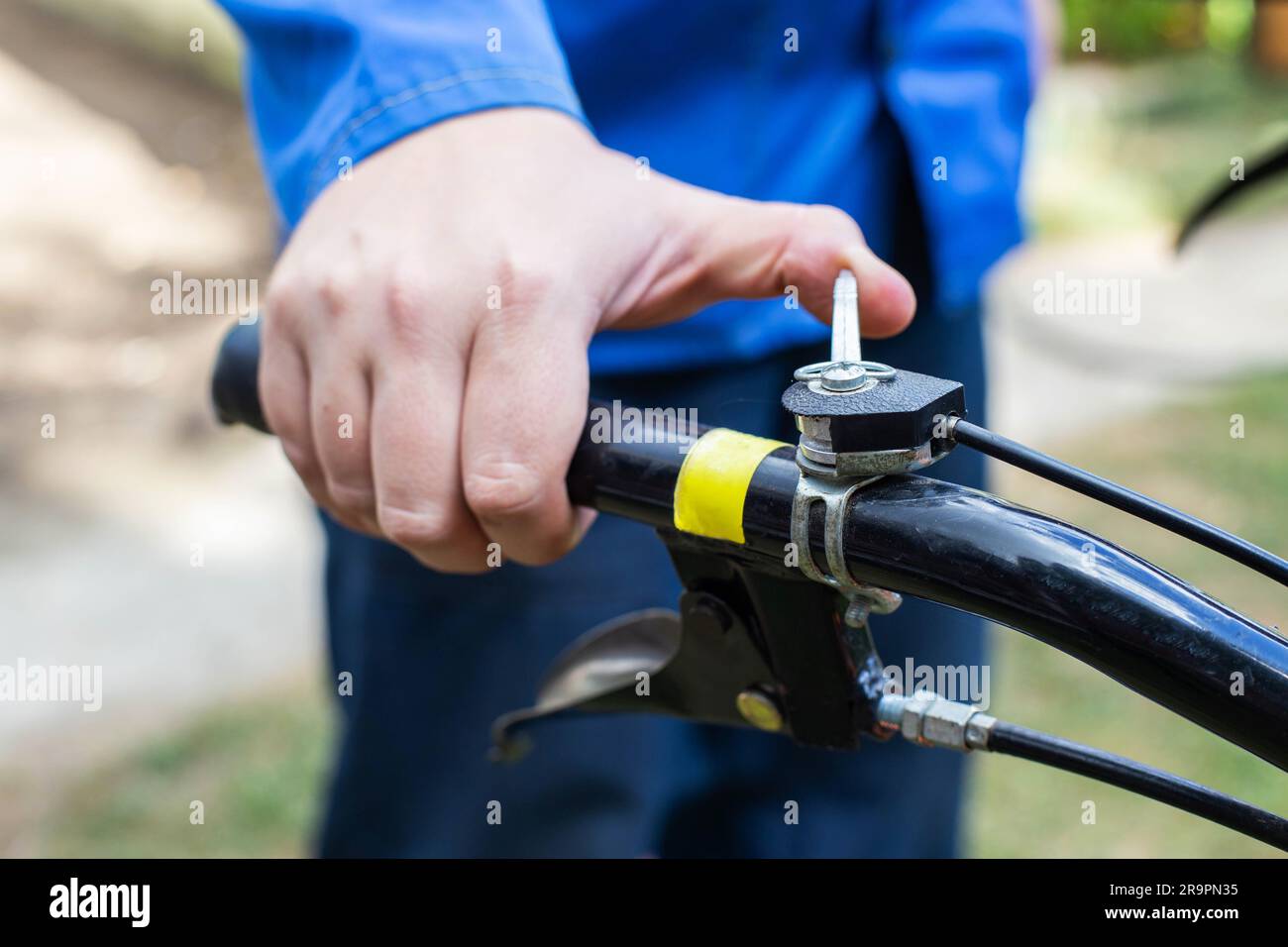 A man adjusts the throttle on the handle of a walk-behind tractor ...