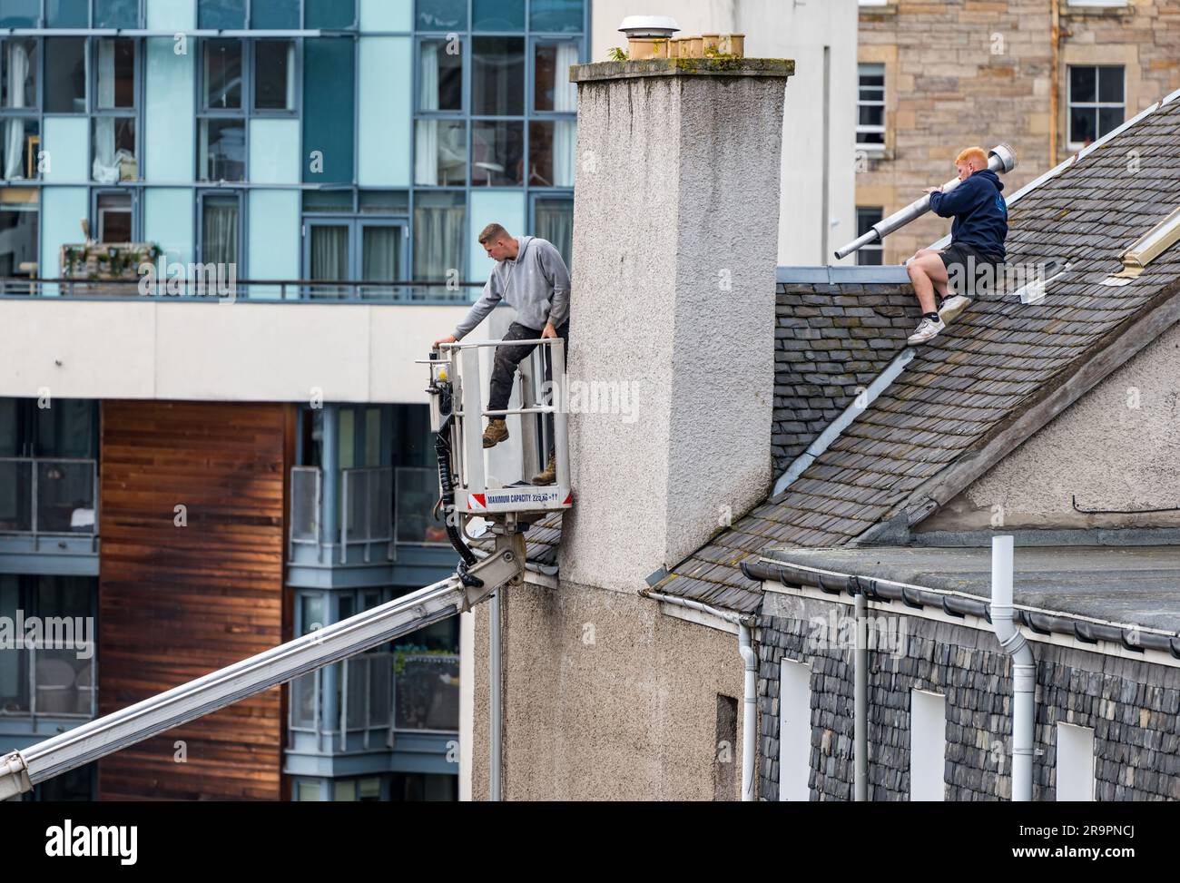 Workmen in cherry picker replacing roof vent, Leith, Edinburgh ...