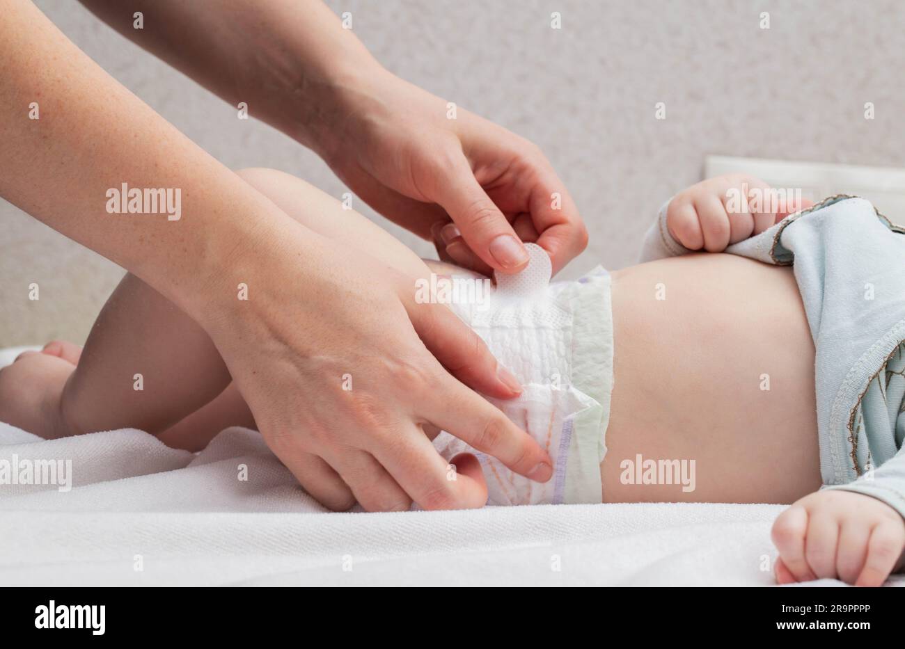 The mother fastens the fasteners and changes the baby's diaper, close ...