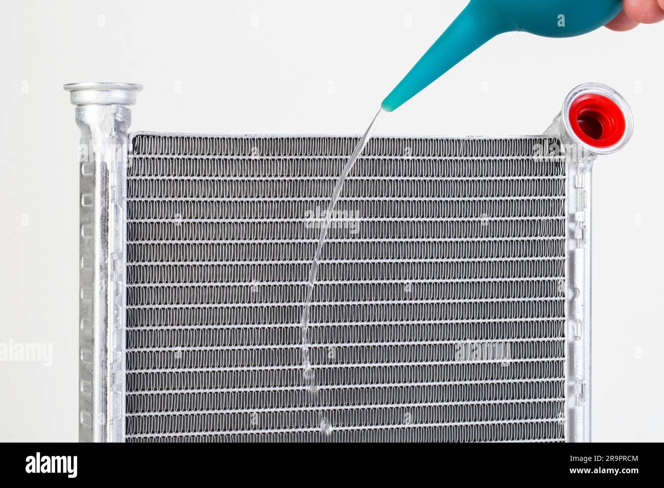 A jet of water from a syringe pours onto a car radiator. The concept of ...