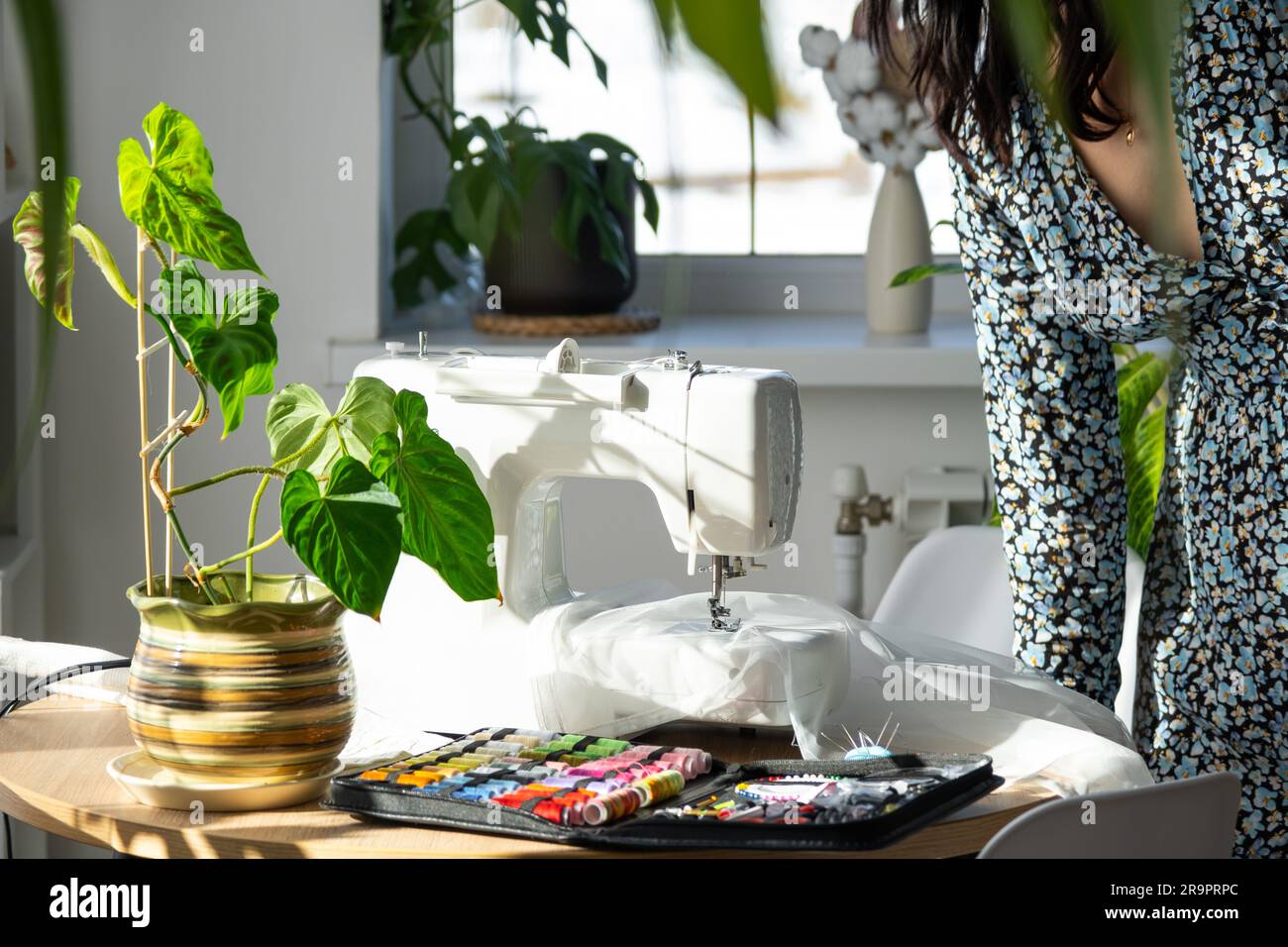 A woman sews tulle on an electric sewing machine in a white modern ...