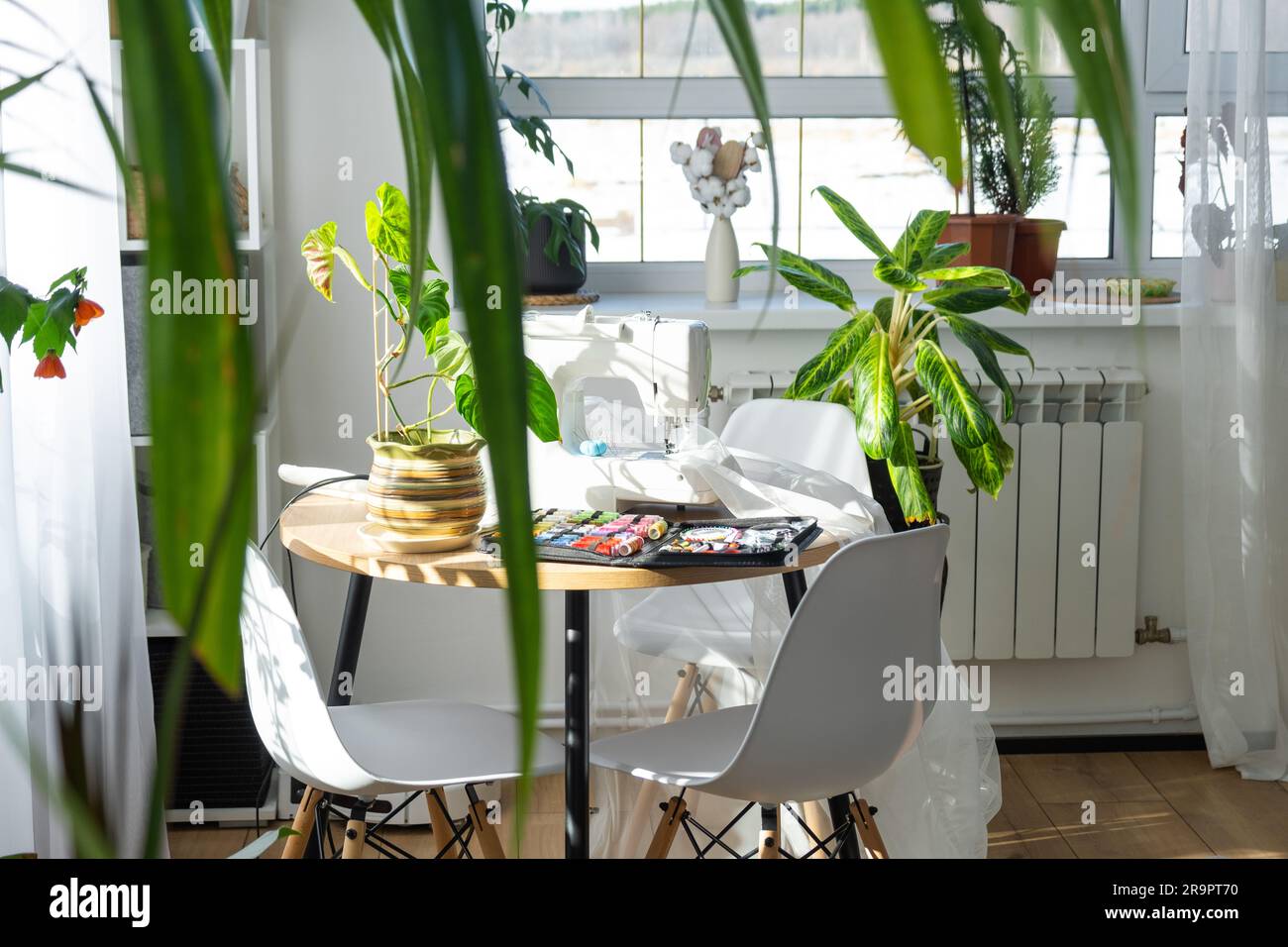 Sewing machine on a round table in the white interior of the house near ...