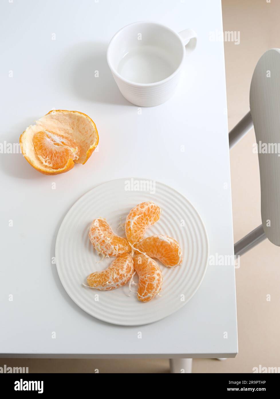 A ripe tangerine fruit cut into sections with a white cup, placed on a ...