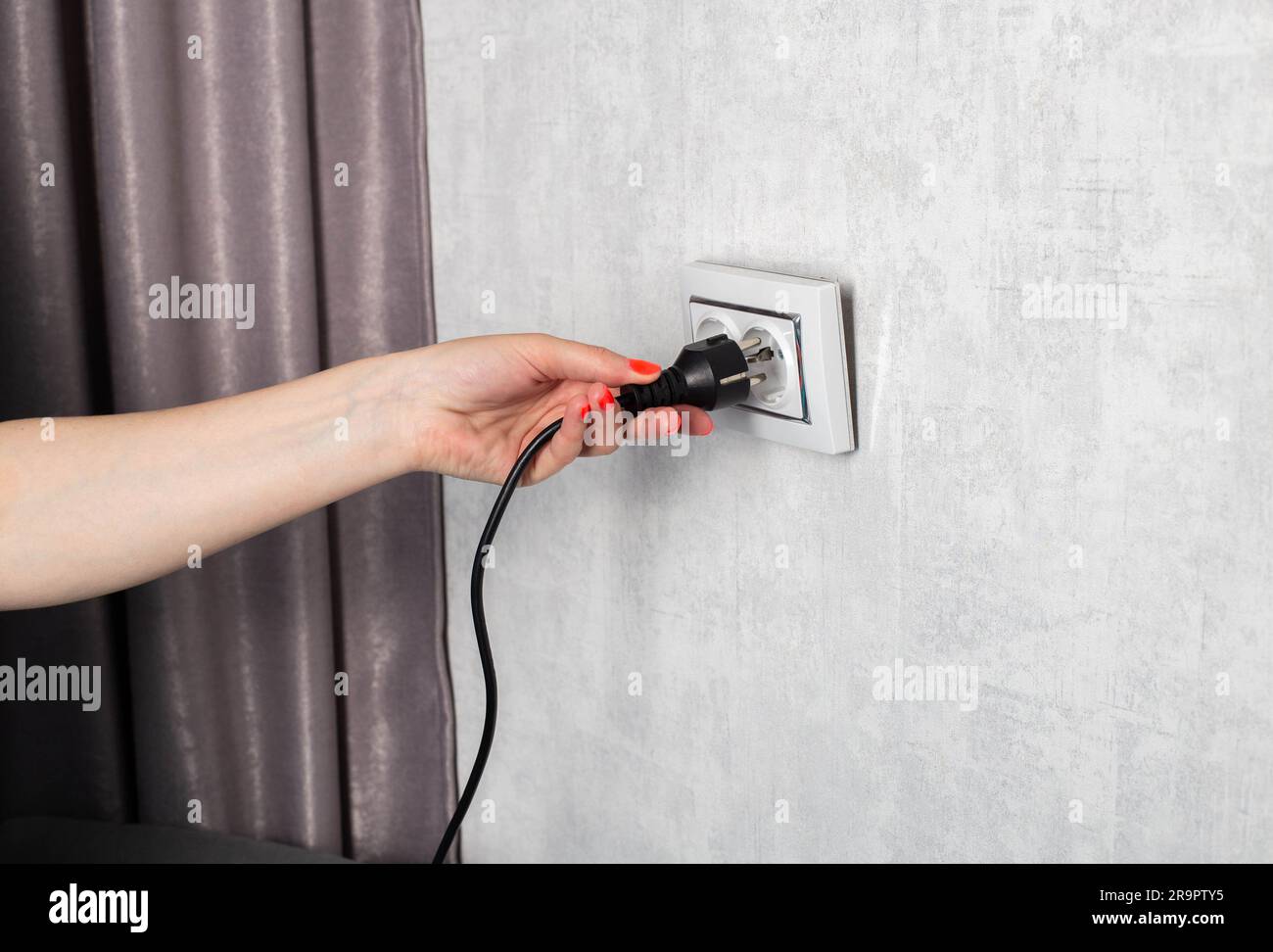 The girl incorrectly removes the electric plug from the socket and ...