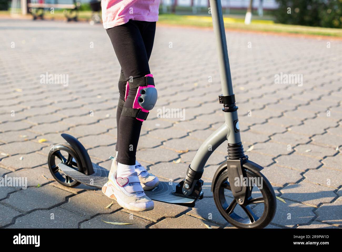 Legs of a child in protective knee pads who rides a scooter. Safety in ...