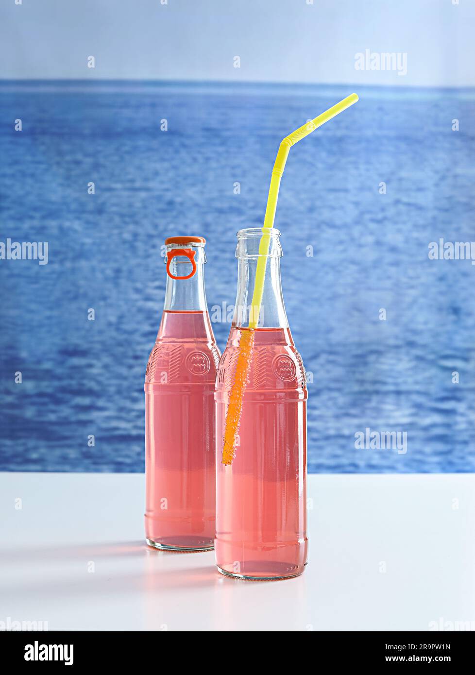 Two bottles of vibrant pink soda displayed on a table overlooking a ...