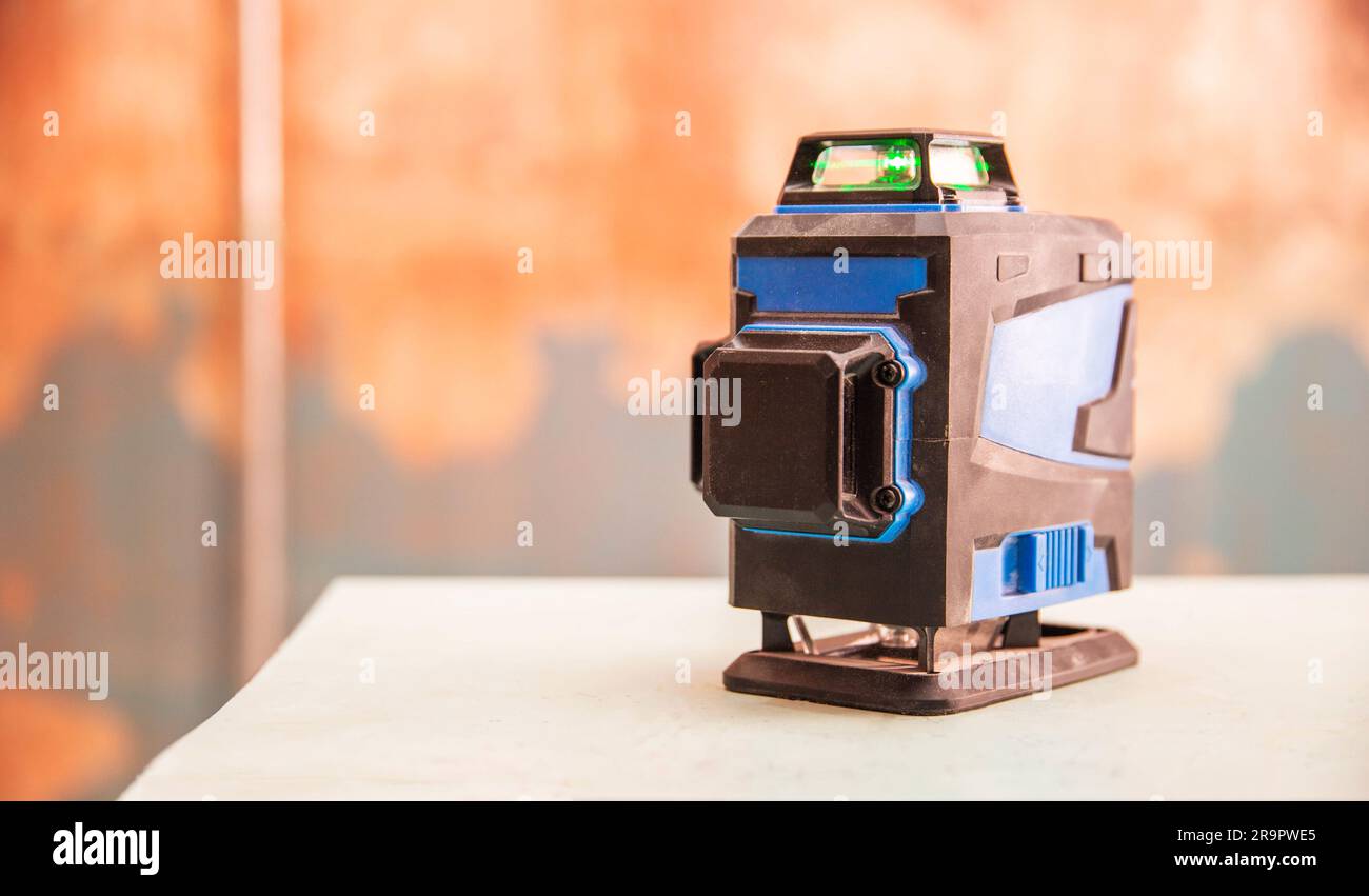 Modern construction laser level against the background of a wall with a concrete contact primer ...