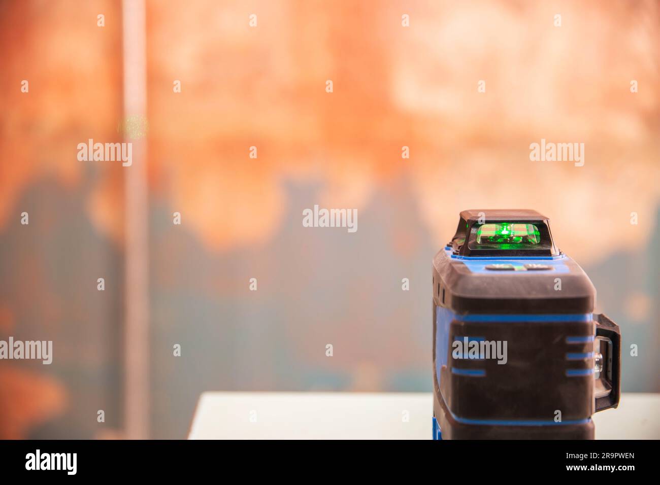 Modern construction laser level against the background of a wall with a concrete contact primer ...