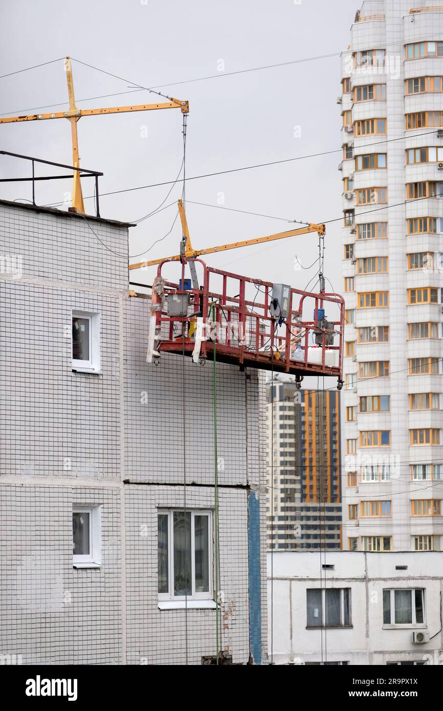 Break during work. Empty construction cradle on metal cables on the ...