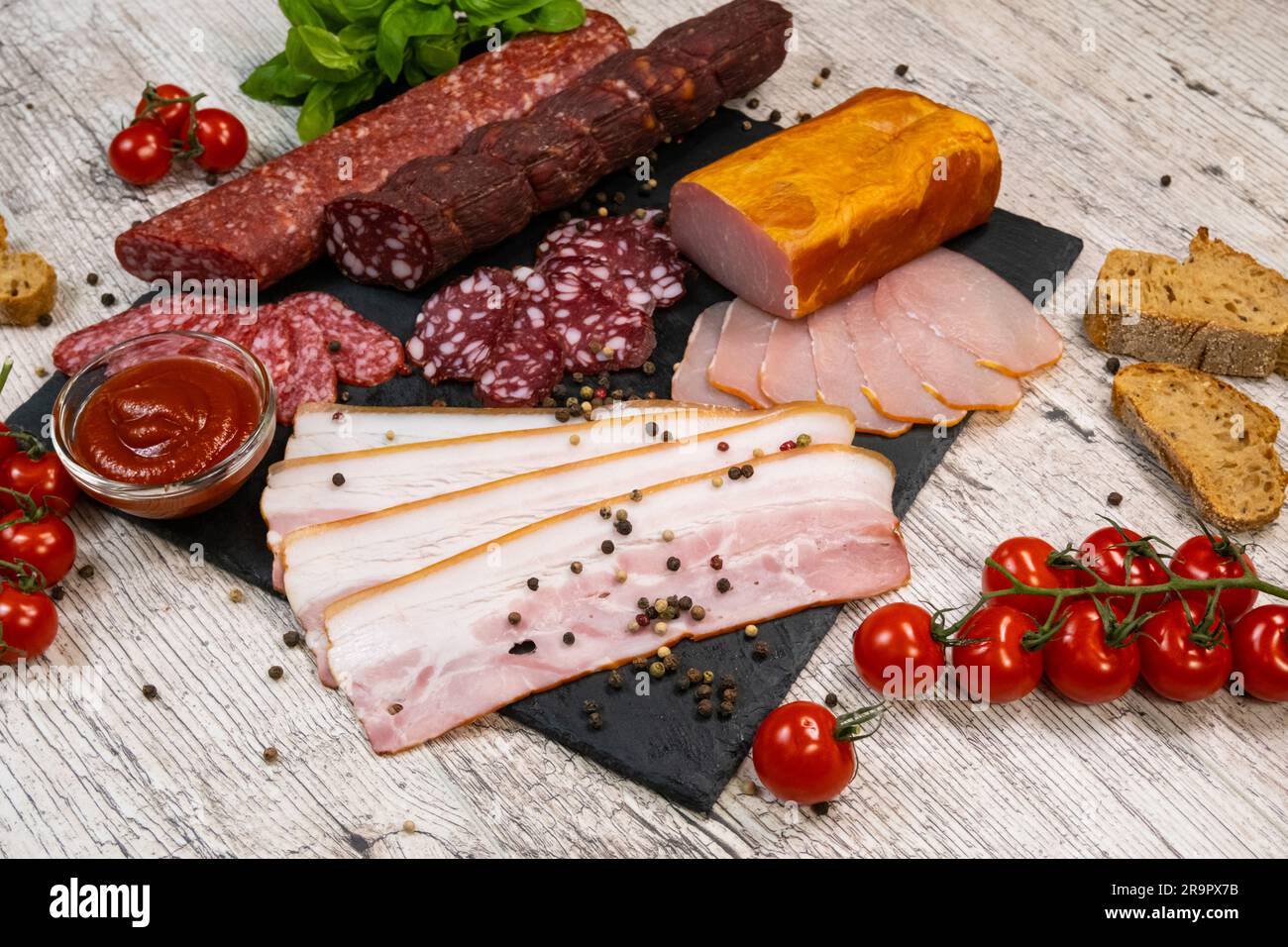 Antipasti different types of sausages and lard on a graphite board .Top ...