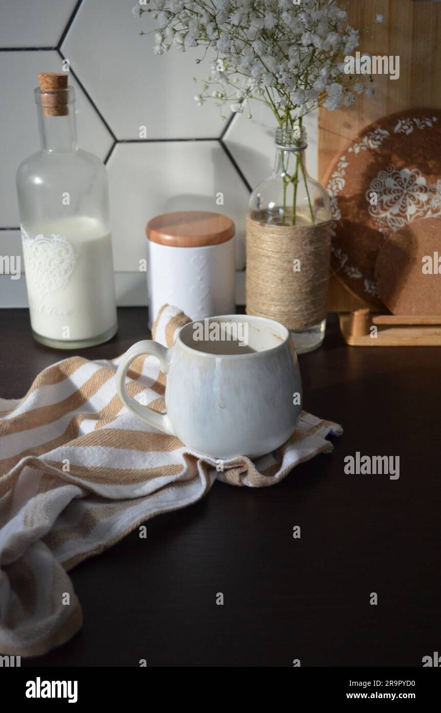A coffee cup with remains on the kitchen countertop near rustic vase ...