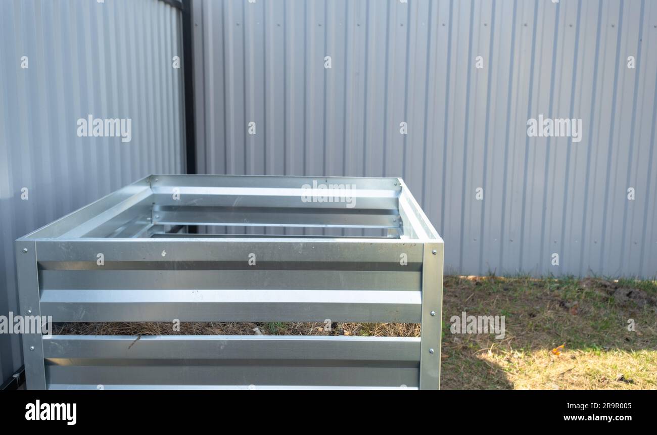 Composter made of metal for organic waste near the fence on suburban ...
