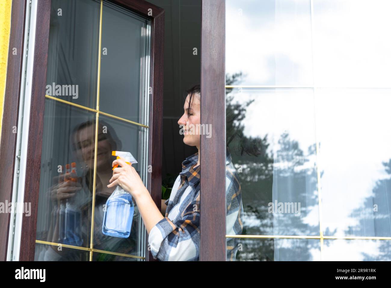 A woman manually washes the window of the house with a rag with a spray ... A woman manually washes the window of the house with a rag with a spray ...