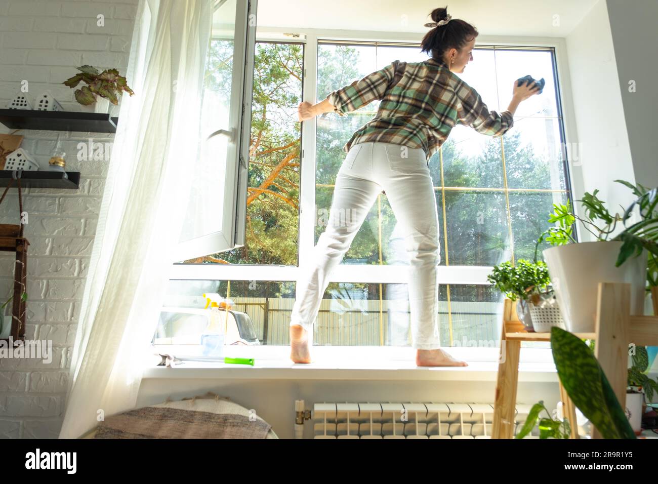 Woman manually washes the window of the house with a rag with spray ...